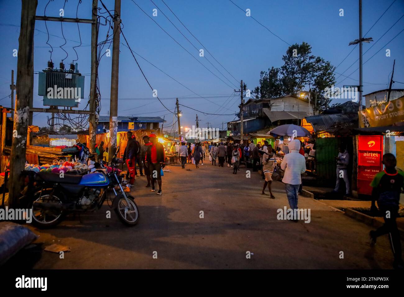 Residents walk past the busy business streets in Kibera Slum, Nairobi ...