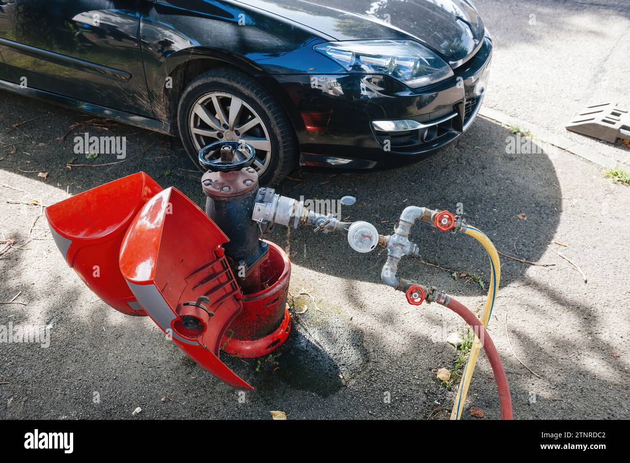 hydrant in full operation near a sleek black car. This juxtaposition of ...