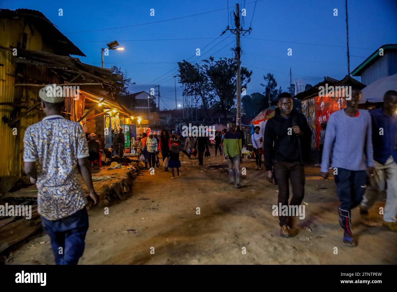 Residents walk past the busy business streets in Kibera Slum, Nairobi ...