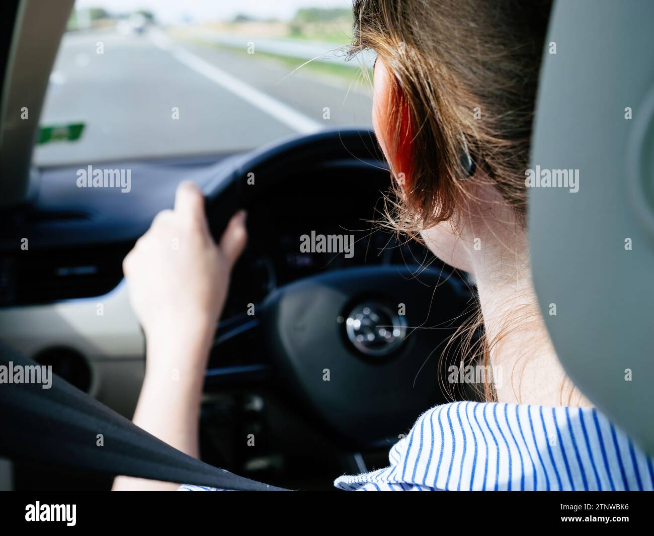 Rear view from the passenger seat of a woman driving a luxury car on ...