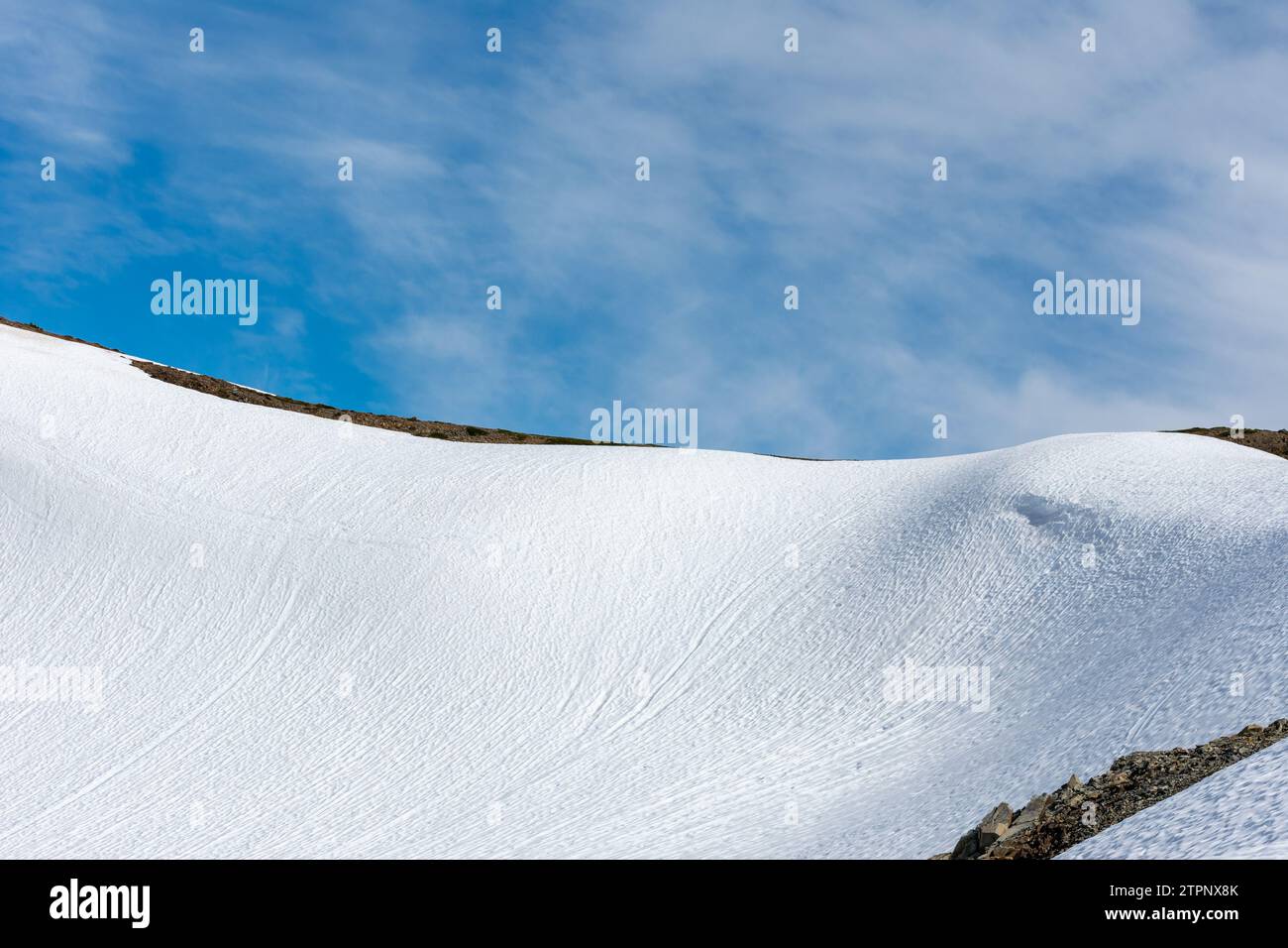 A crisp snowdrift curves against a vivid blue sky in British Columbia ...