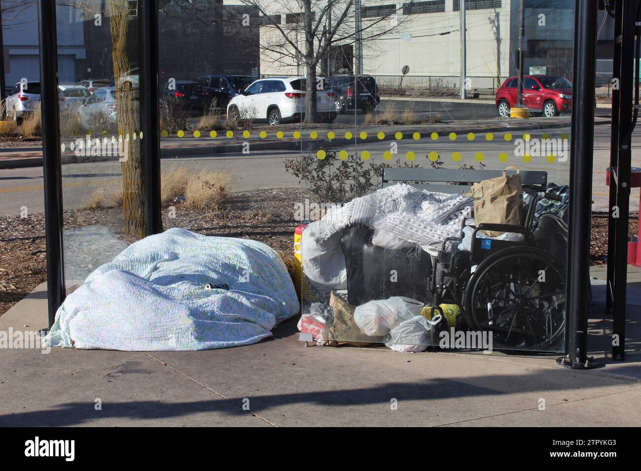 Homeless person unseen under blankets in a bus shelter with a ...