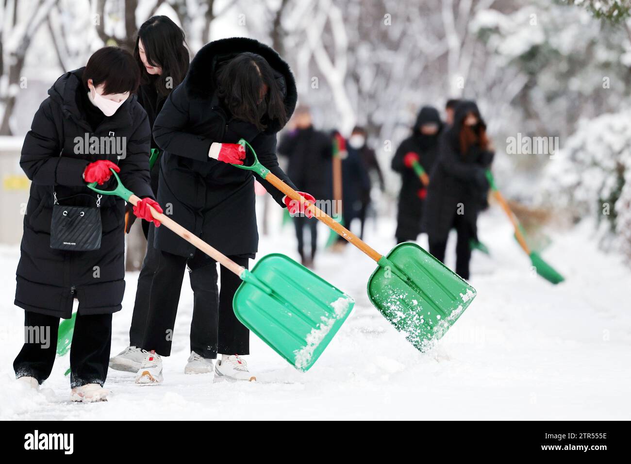 21st Dec, 2023. Heavy snow Teachers remove snow on a sidewalk near an ...