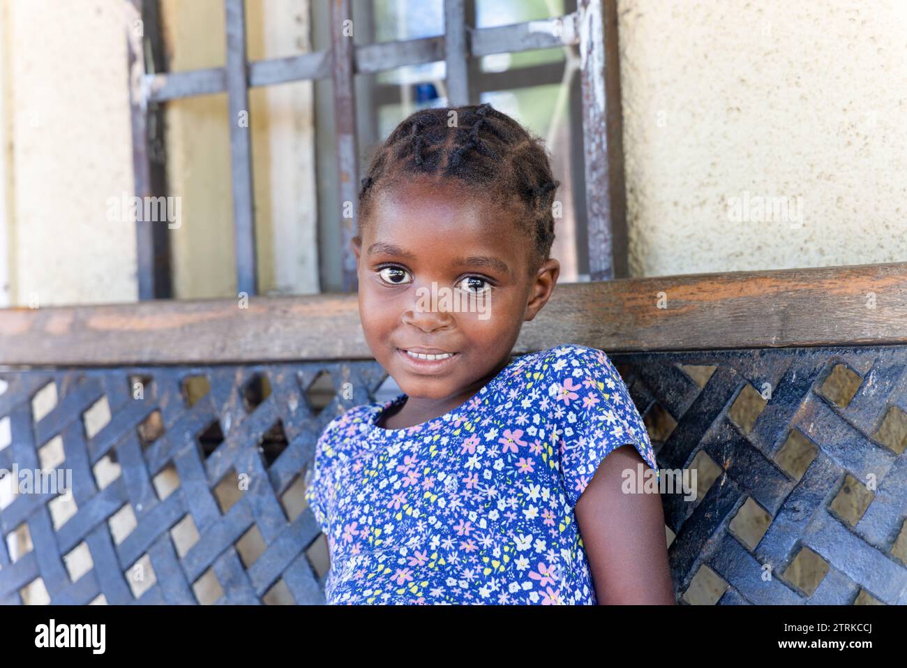 portrait of a young african child, braids hairstyle, burglar bars inn ...