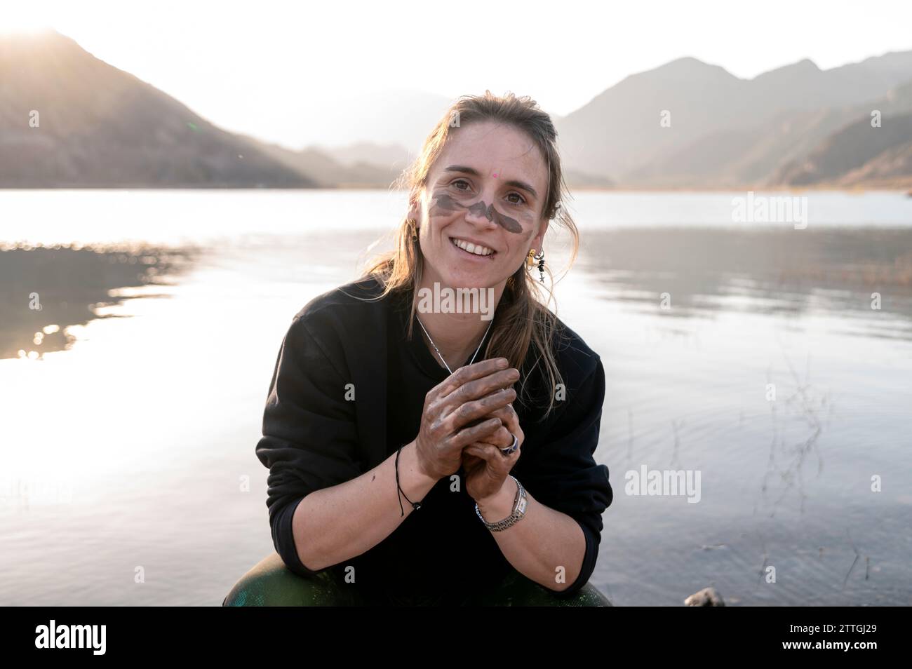 Woman putting mud on hands and face while enjoying outdoors in nature ...