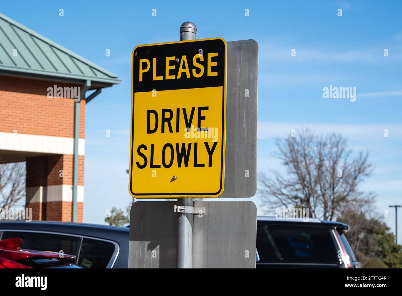 Yellow and black Drive Slowly warning sign on metal pole Stock Photo ...