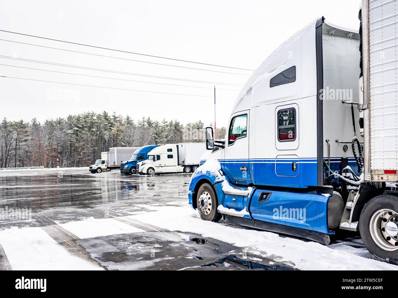 Big rig semi trucks with semi trailers standing in row on the half ...