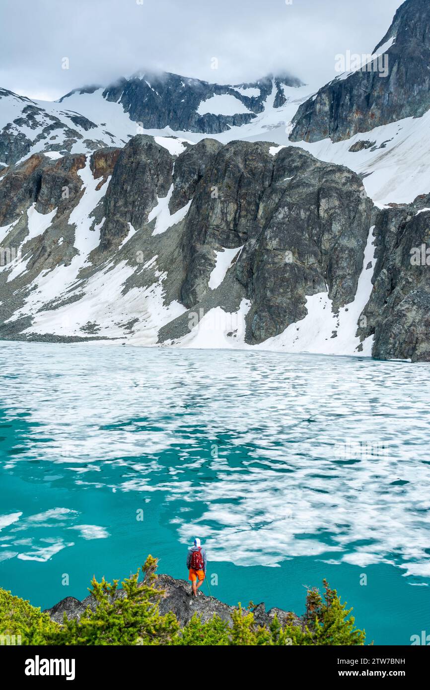 Adventurous hiker in red overlooks the frozen beauty of Wedgemount Lake ...