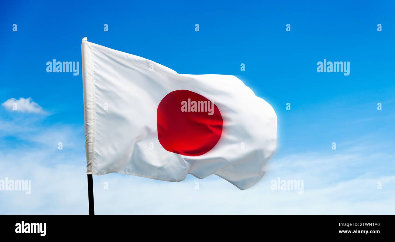 Japan flag waving on blue sky background Stock Photo - Alamy