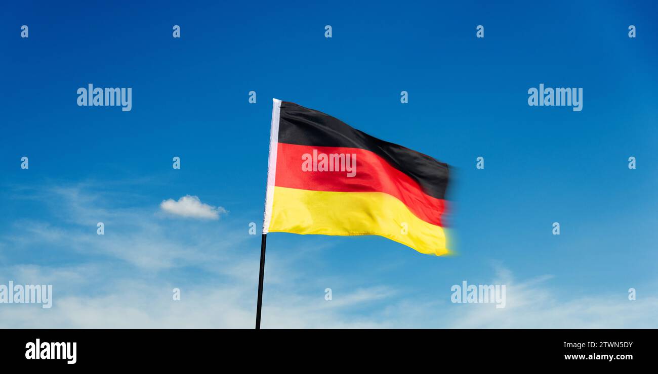 German flag waving against blue sky background Stock Photo - Alamy