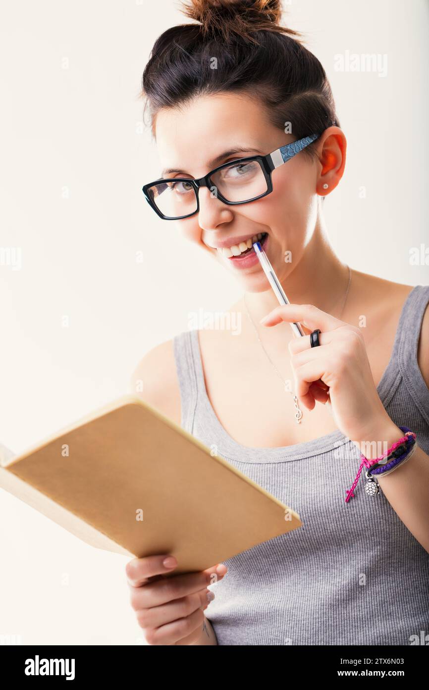 Deep in contemplation, she holds her notebook and pen, a portrait of ...