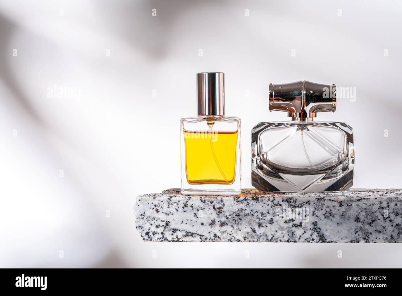 Perfume bottle on granite stones against white background with shadows ...