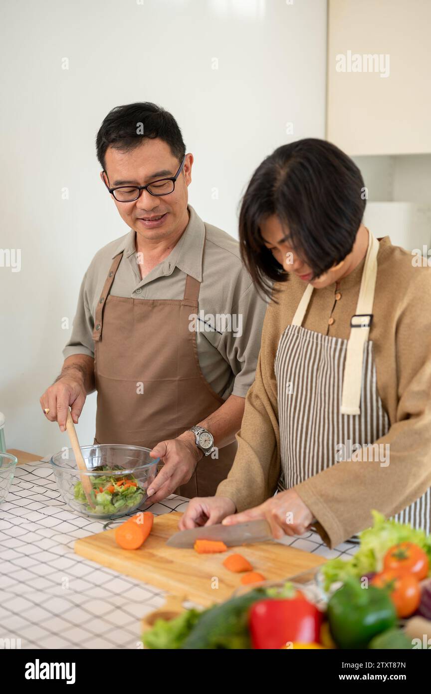 Lovely adult Asian husband and wife enjoy cooking, making a healthy ...