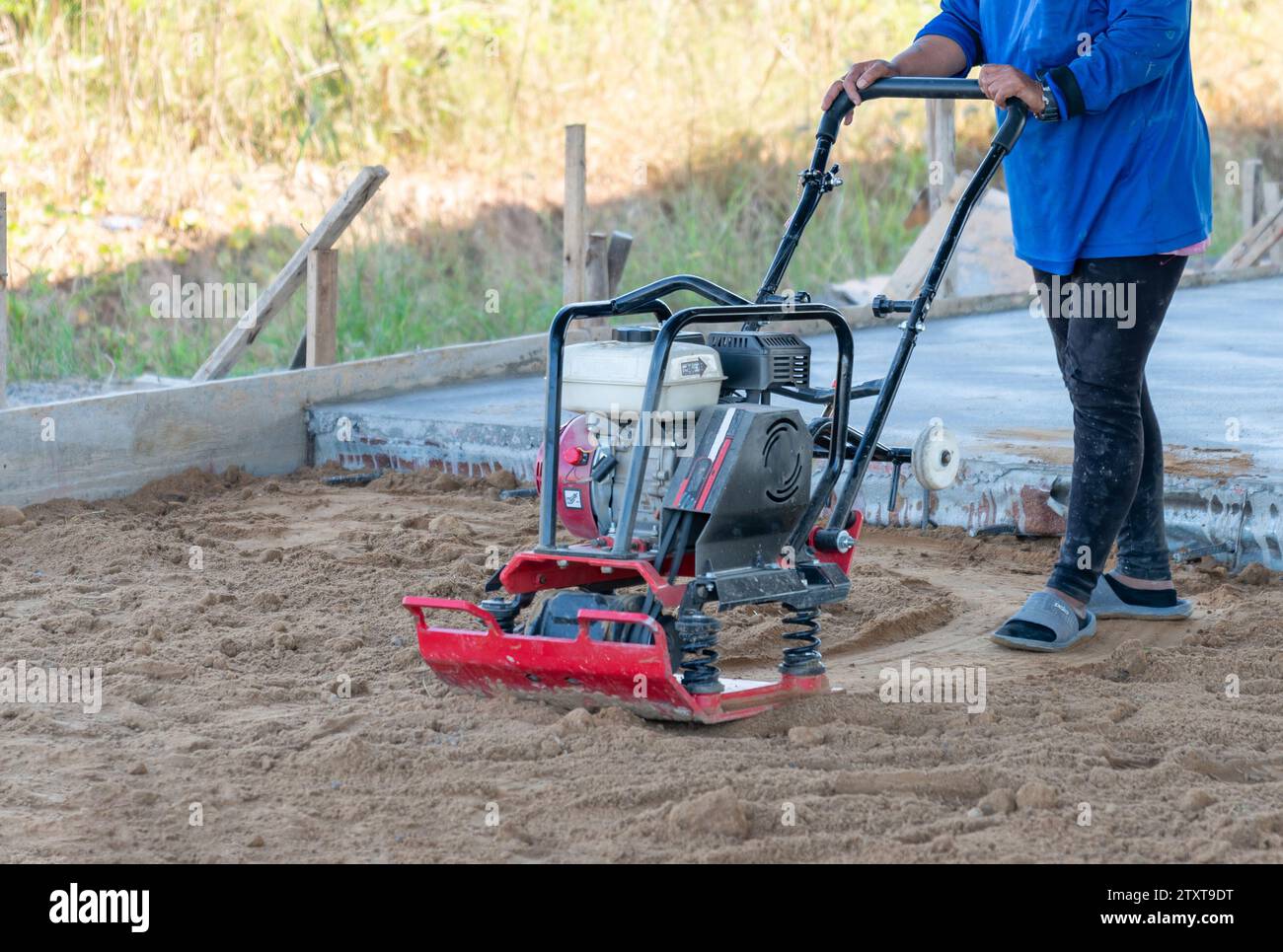 Worker in use vibratory plate compactor for compaction sand. Industrial ...