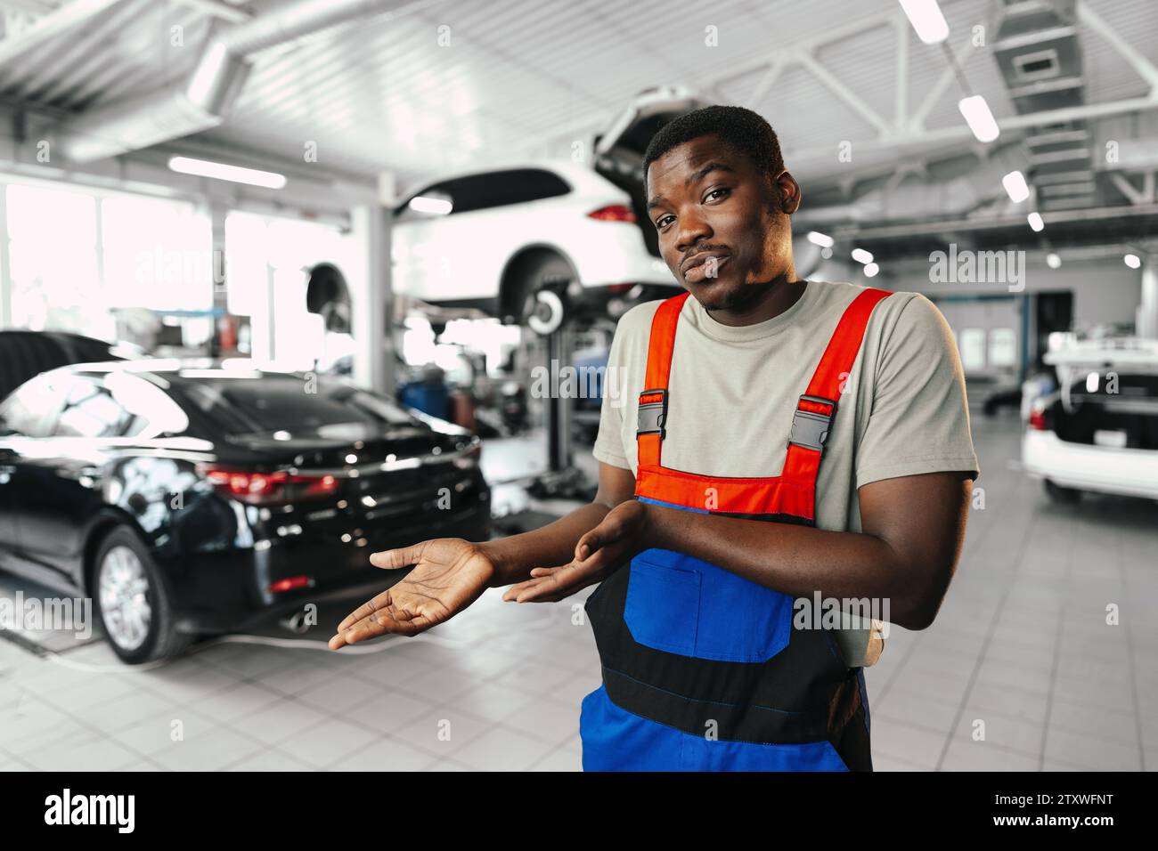 African man mechanic in uniform at the car repair station, portrait ...