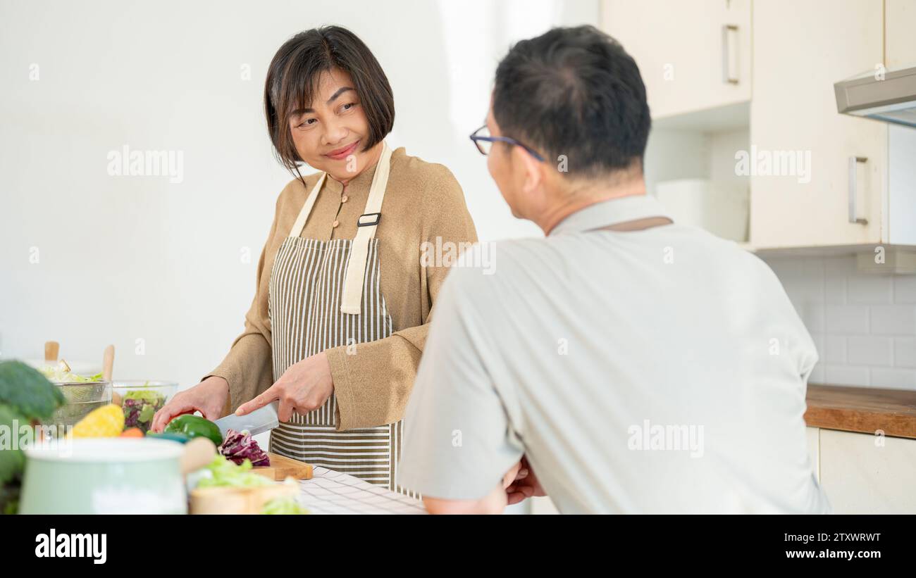 A happy Asian husband is enjoying talking with his wife while she is ...