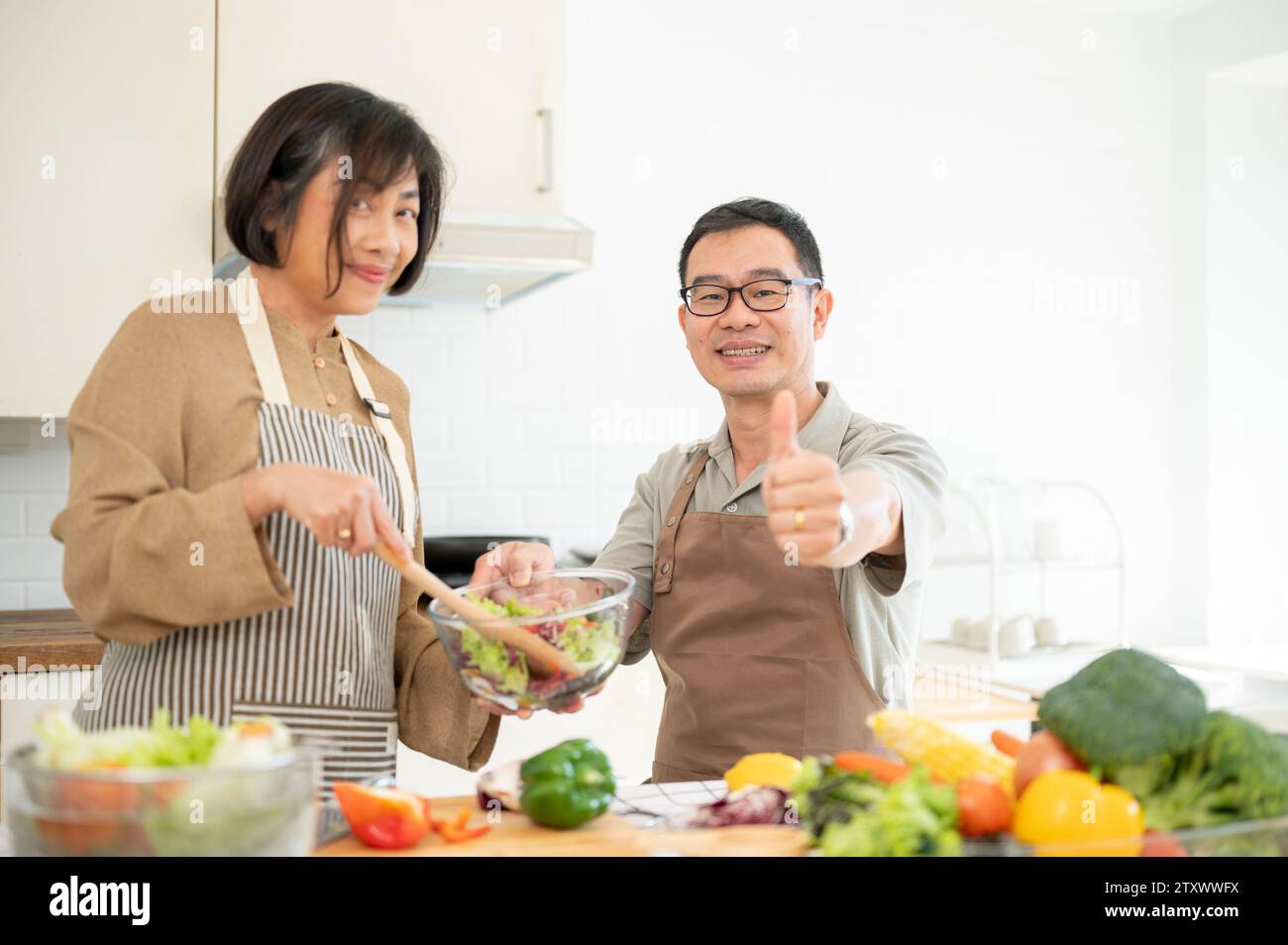 A happy adult Asian husband is showing his thumb up to the camera while ...