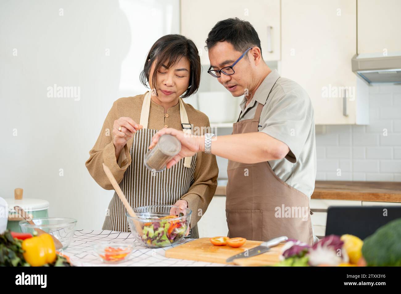 Happy Asian couples, husband and wife, are cooking a healthy salad bowl ...