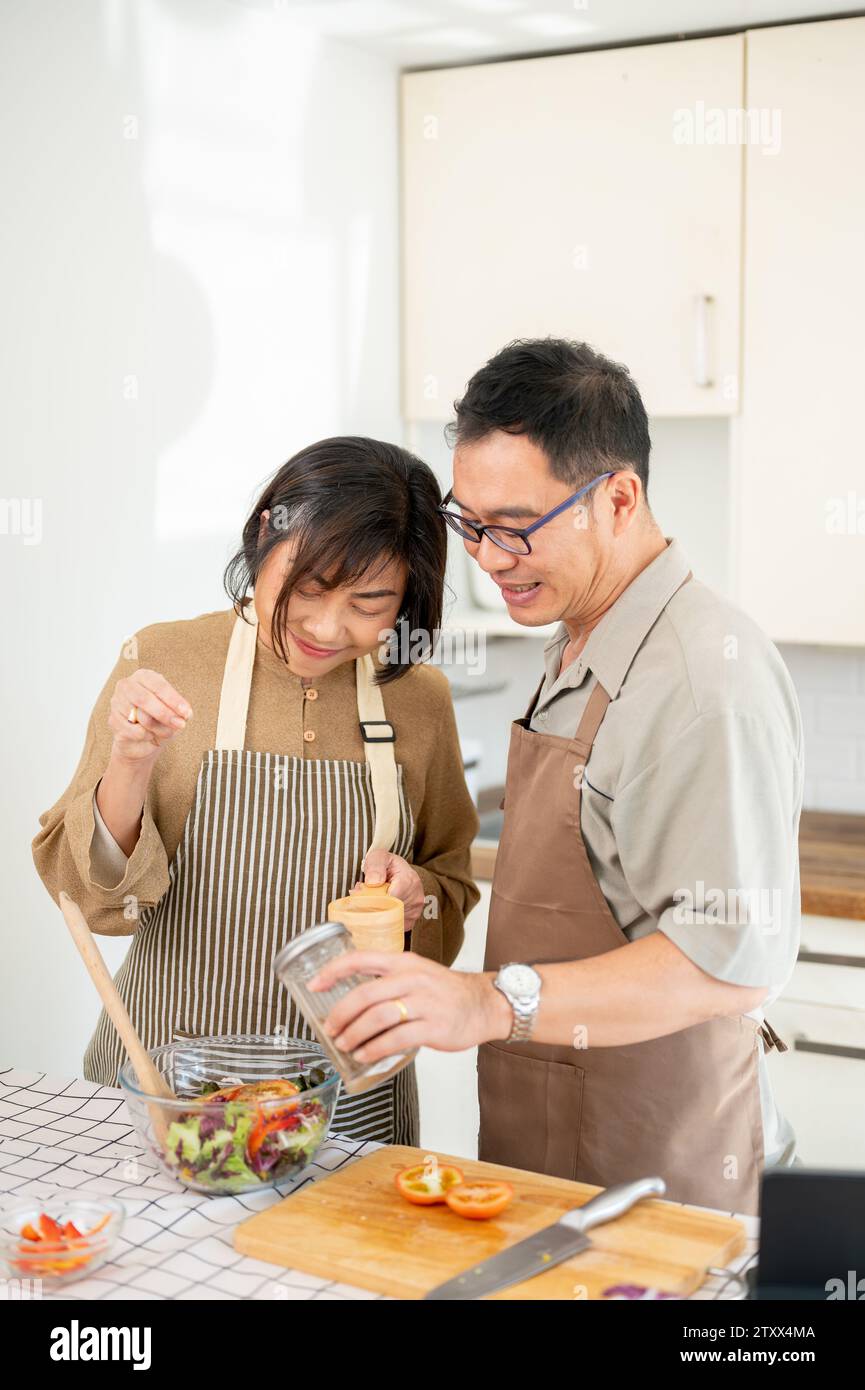 Happy Asian couples, husband and wife, are cooking a healthy salad bowl ...