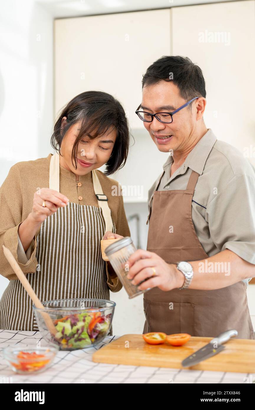 Happy Asian couples, husband and wife, are cooking a healthy salad bowl ...