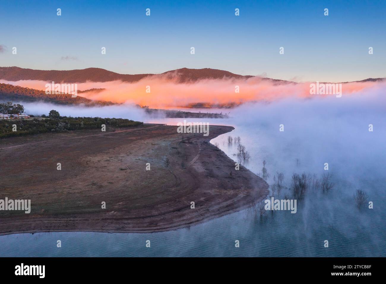 Aerial view of golden dawn light over a fog covered lake at Lake Eildon ...