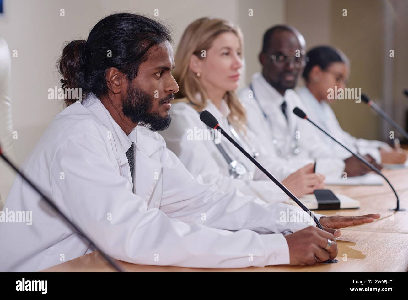 Group of doctors sitting in a row and giving an interview during press ...