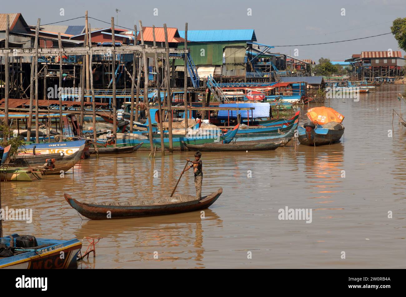 Boy on small boat moving along the waterways, Floating village Kampong ...