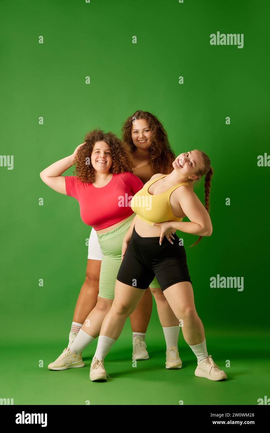 Smiling, beautiful young women with oversize body shapes, in sportswear ...
