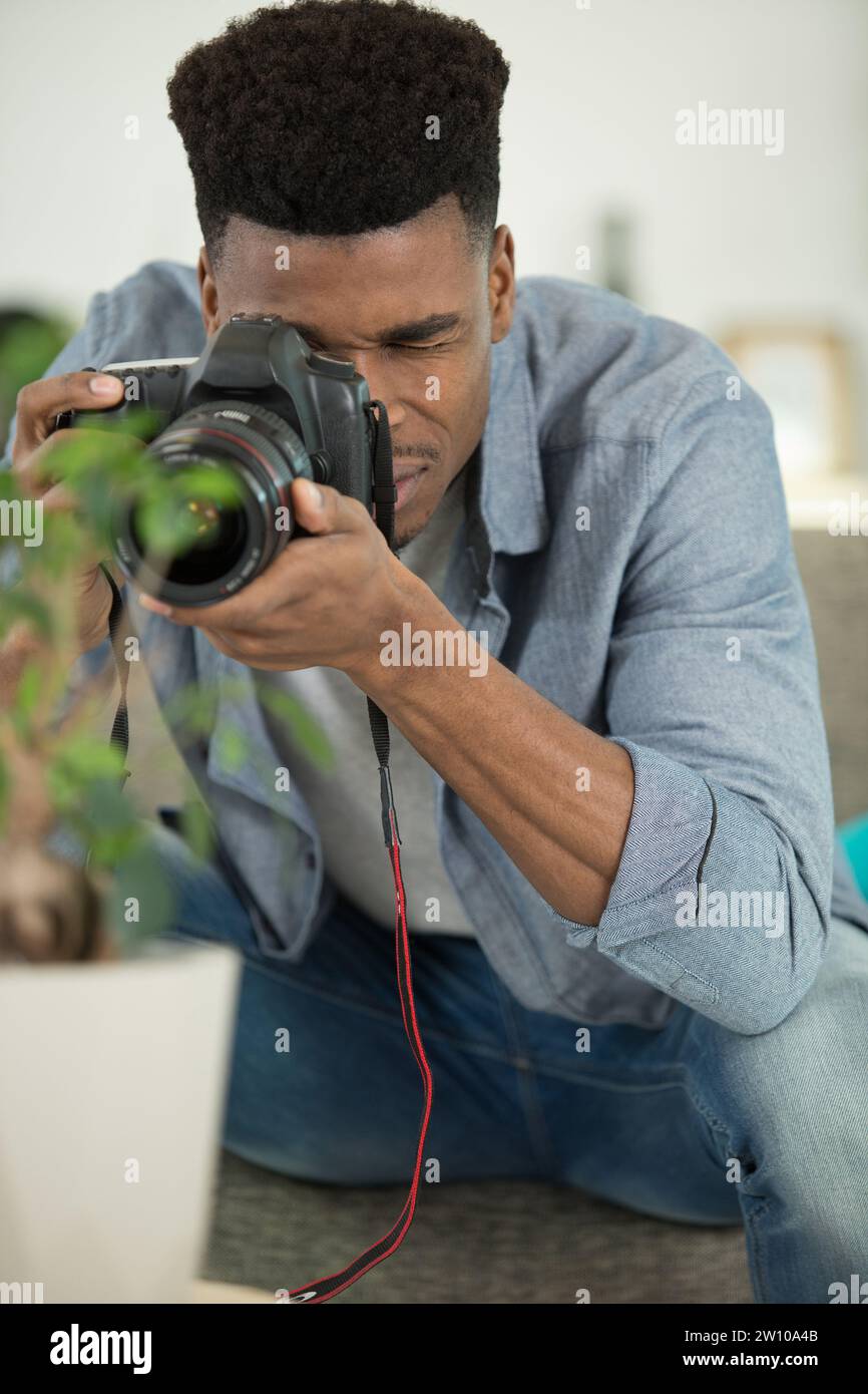 man taking pictures from behind a plant Stock Photo - Alamy