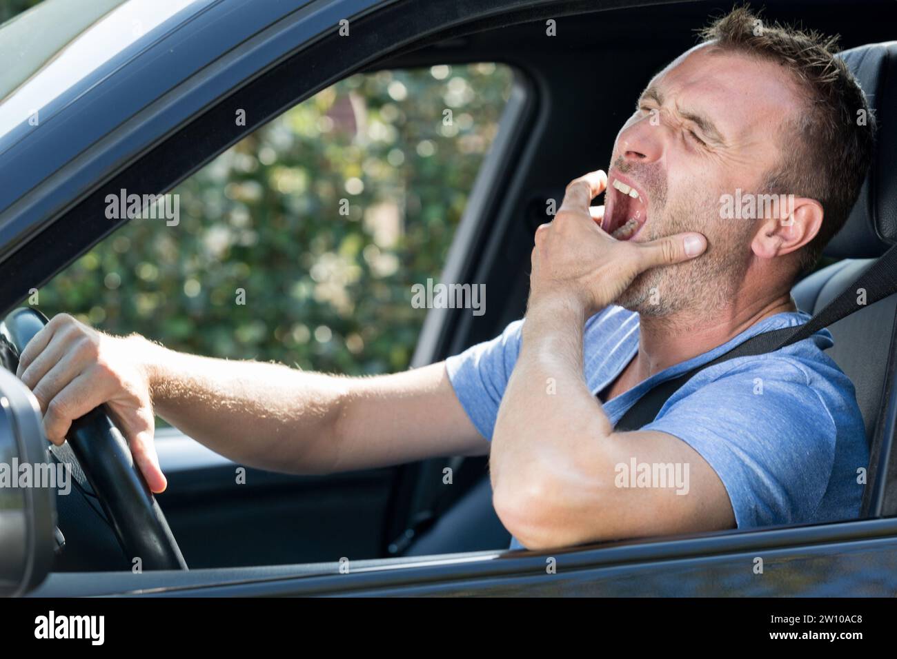 tired yawning man driving his car need a rest Stock Photo - Alamy