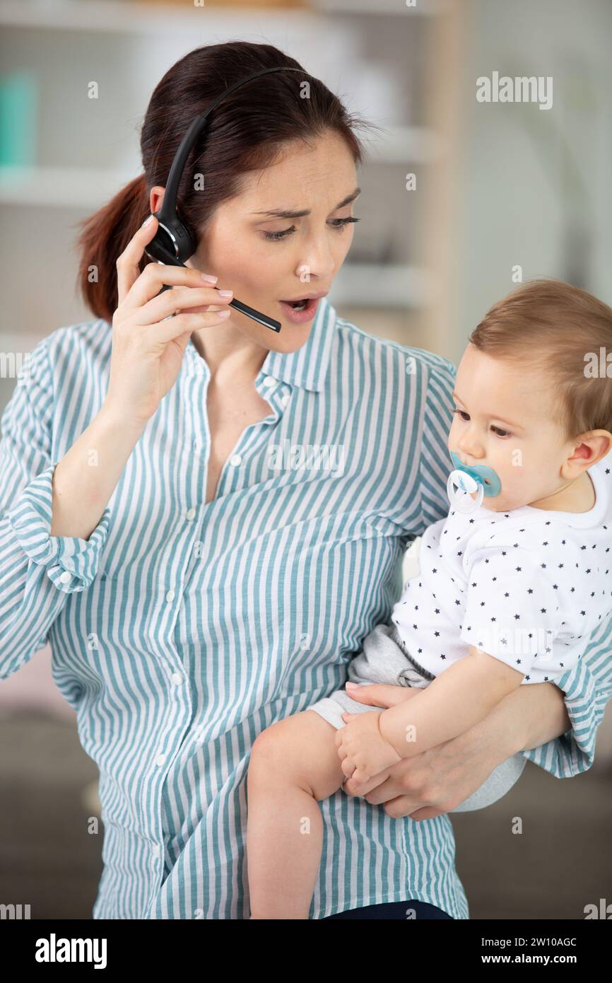 mother stood working holding baby on her hip Stock Photo - Alamy
