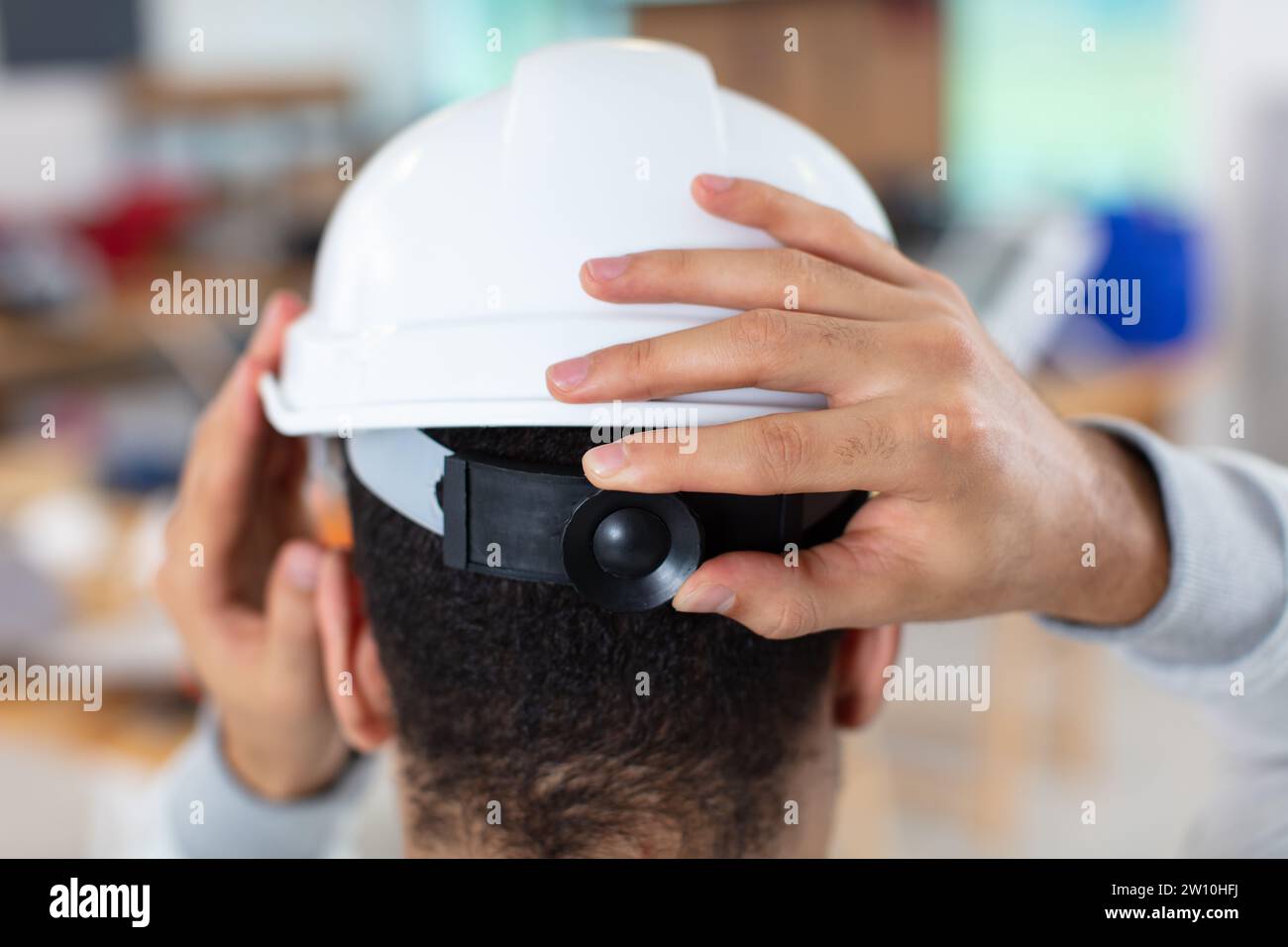 workman adjusting his hard hat to fit correctly Stock Photo - Alamy