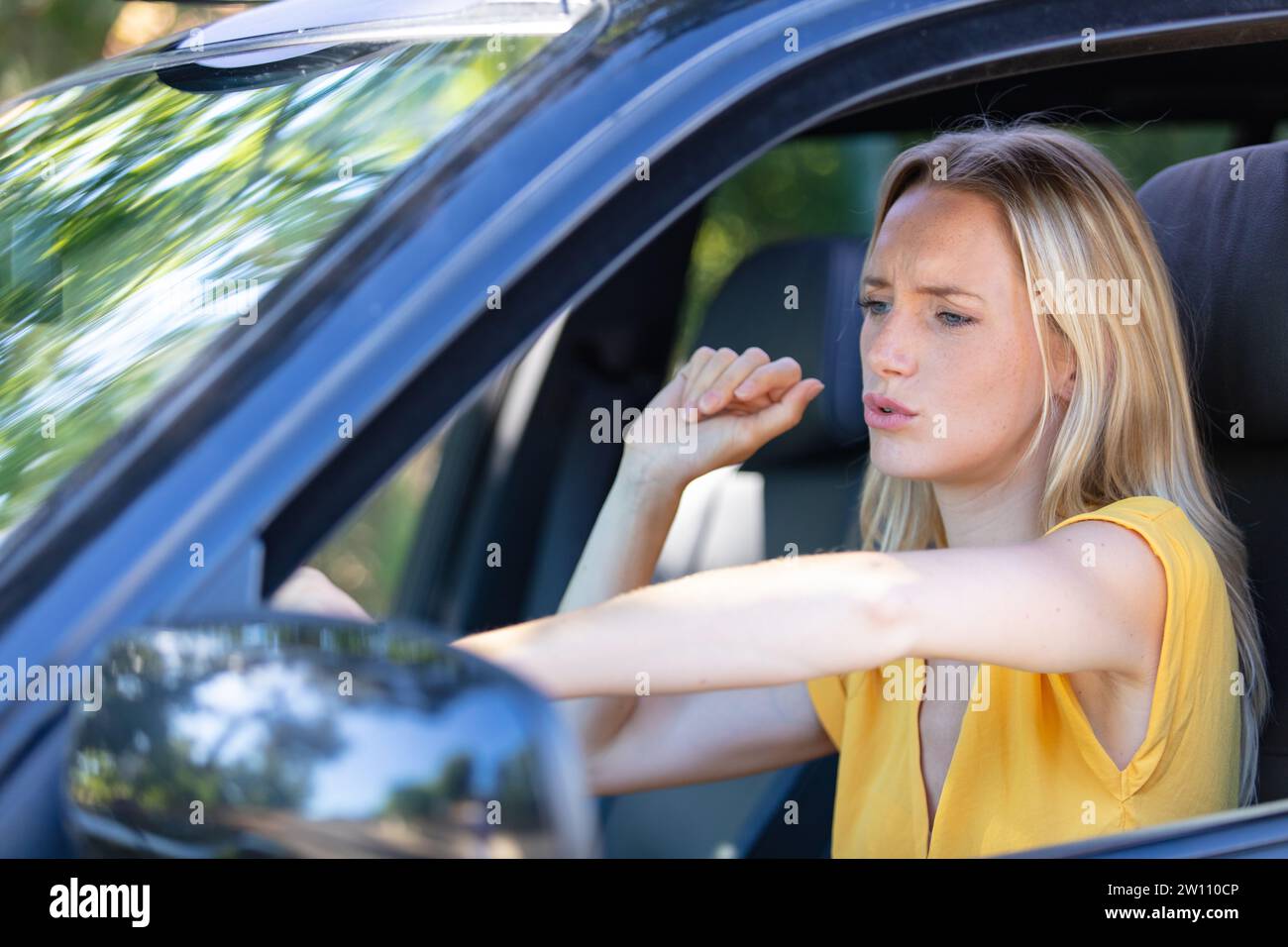 blonde woman makes anxious facial expression while driving Stock Photo ...