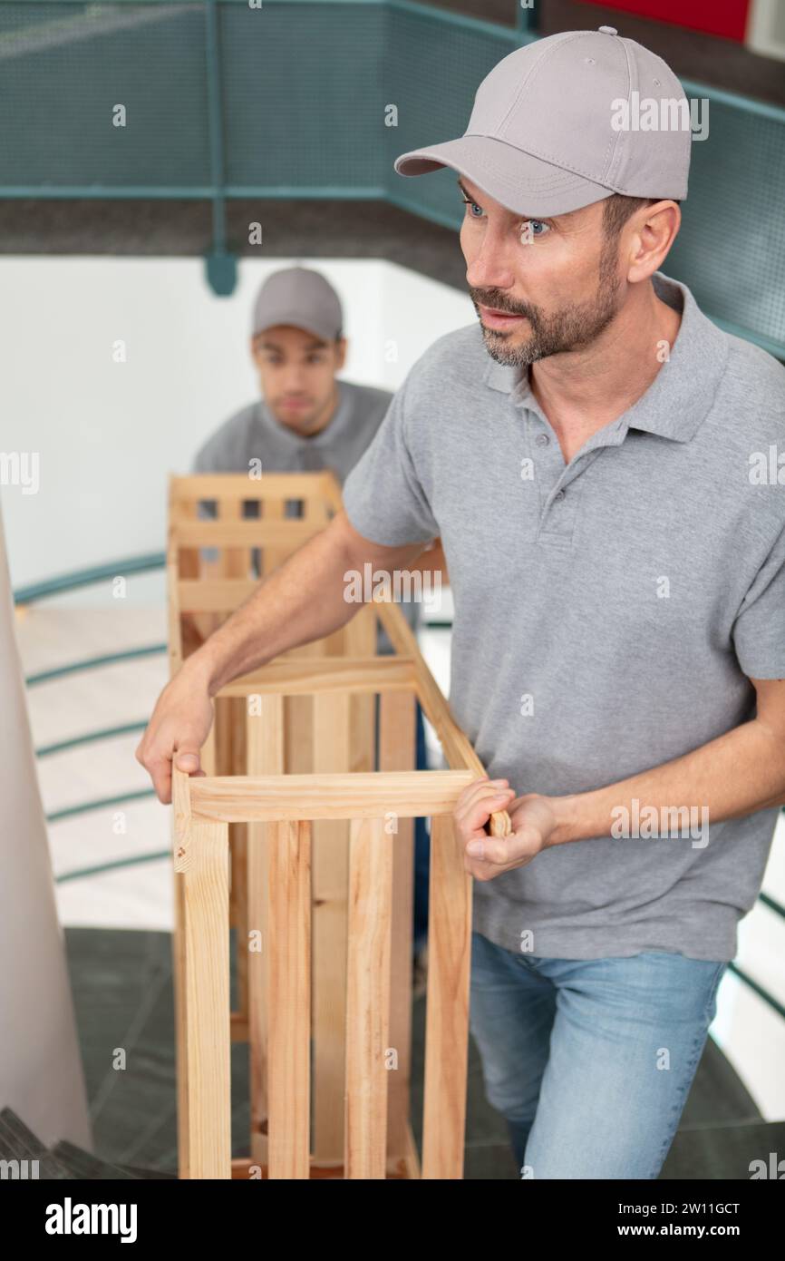 two men carrying a wooden shelf Stock Photo - Alamy