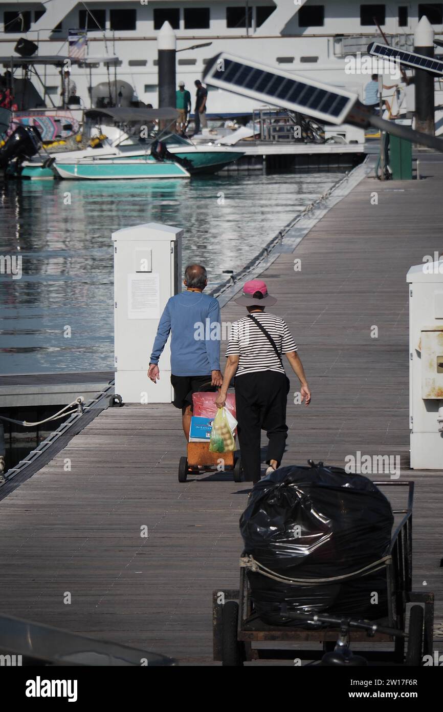 An elderly couple pulling a trolley down a walkway, ready to load the ...