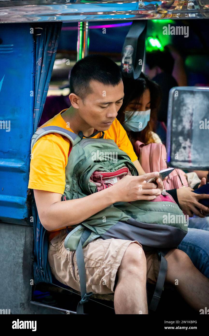 A Filipino man scrolls one his mobile phone sat on a Manila jeepney ...