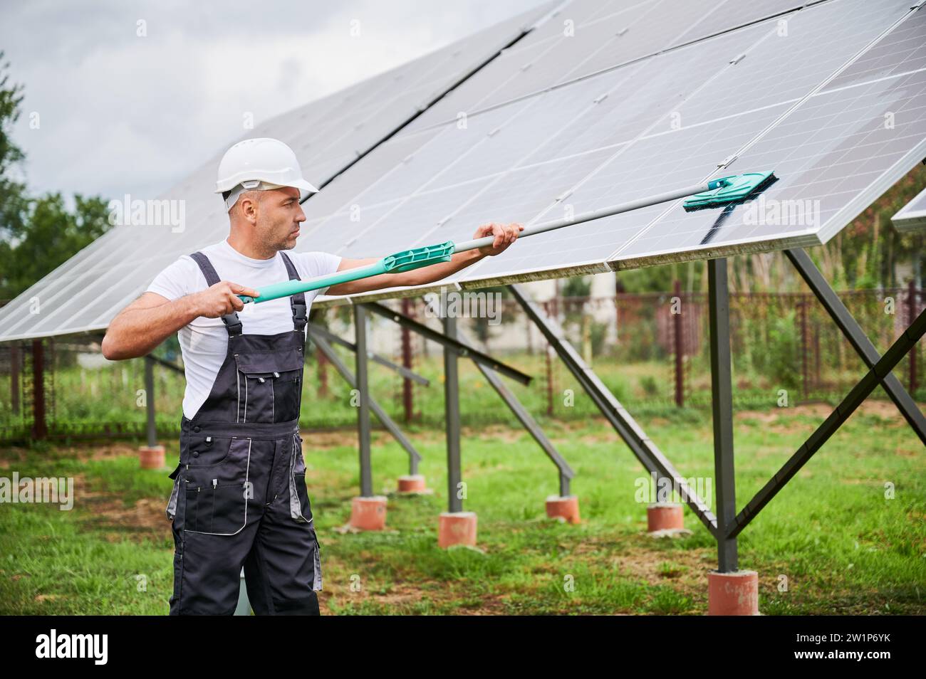 Worker cleaning solar panels from dust outdoors. Taking care about ...