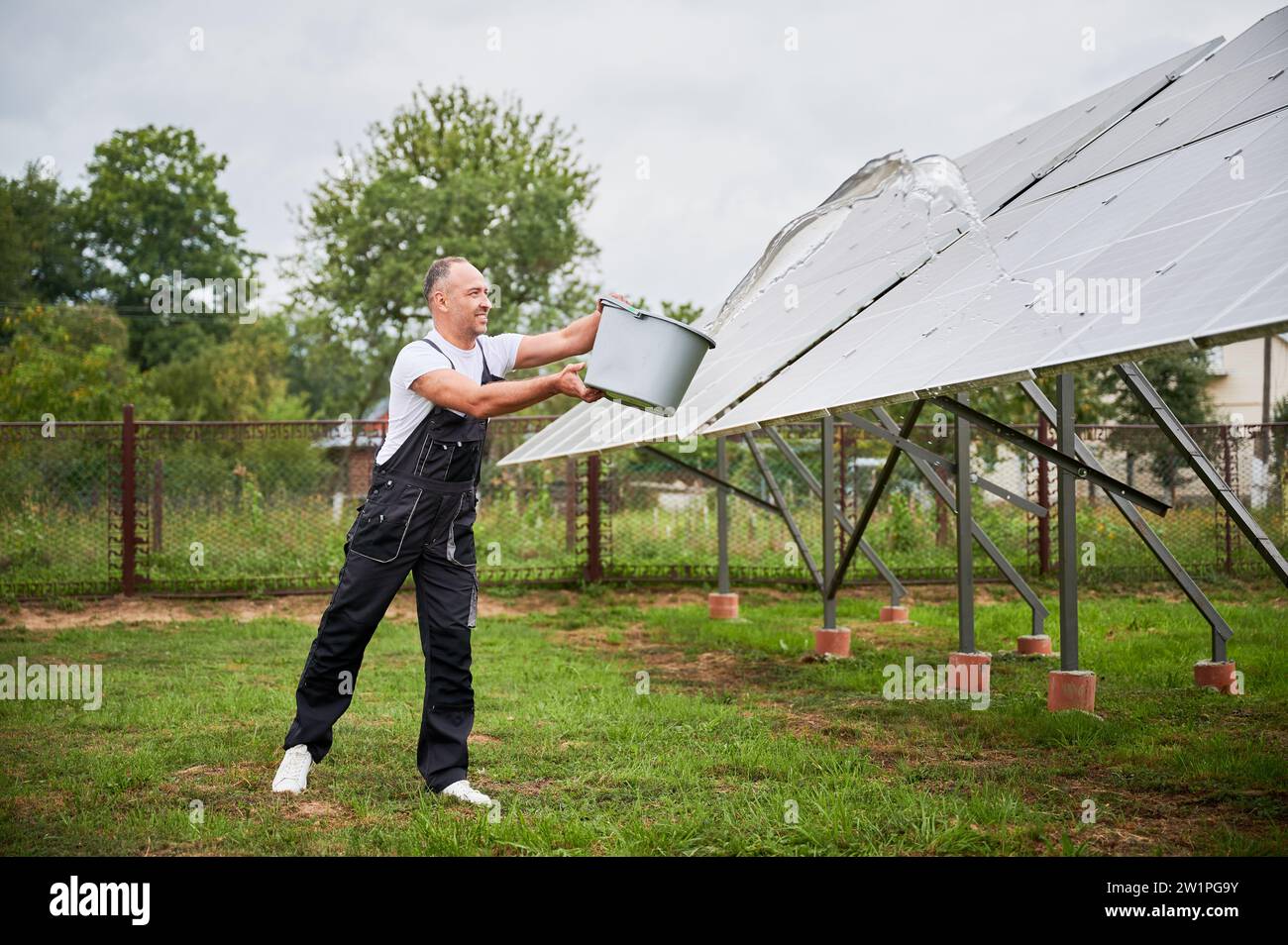 Knowledgeable worker cleaning solar photovoltaic batteries. Man taking ...