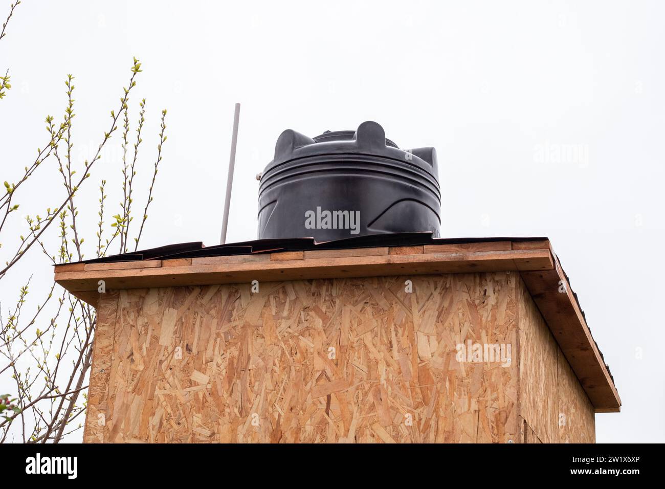 water tank is installed on a wooden shower cabin. Installation of a ...