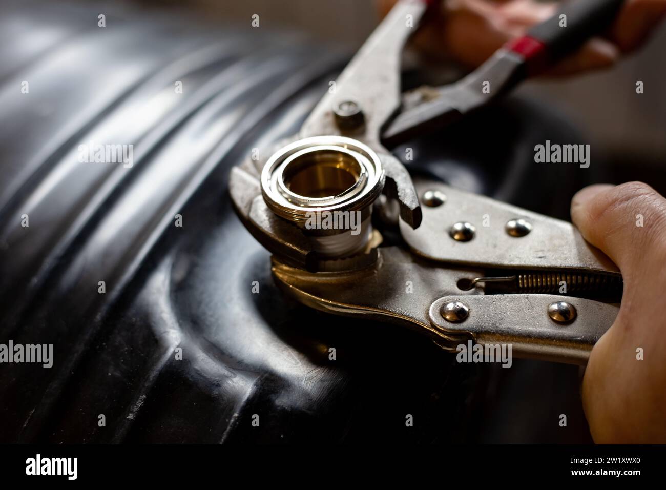 A plumber screws a fitting onto a water tank. Installation of a summer ...