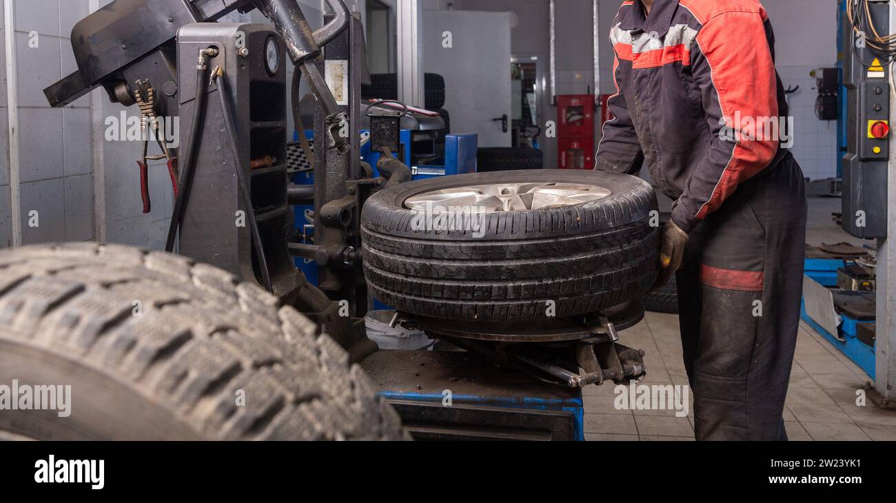 Car mechanic changing tire on the rim in service garage. Close-up of ...