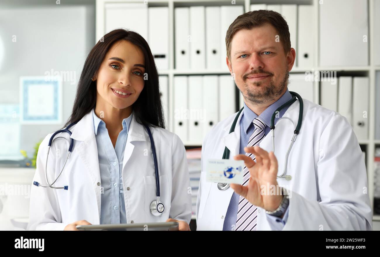 Group of smiling mature caucasian doctors offering special plastic card ...