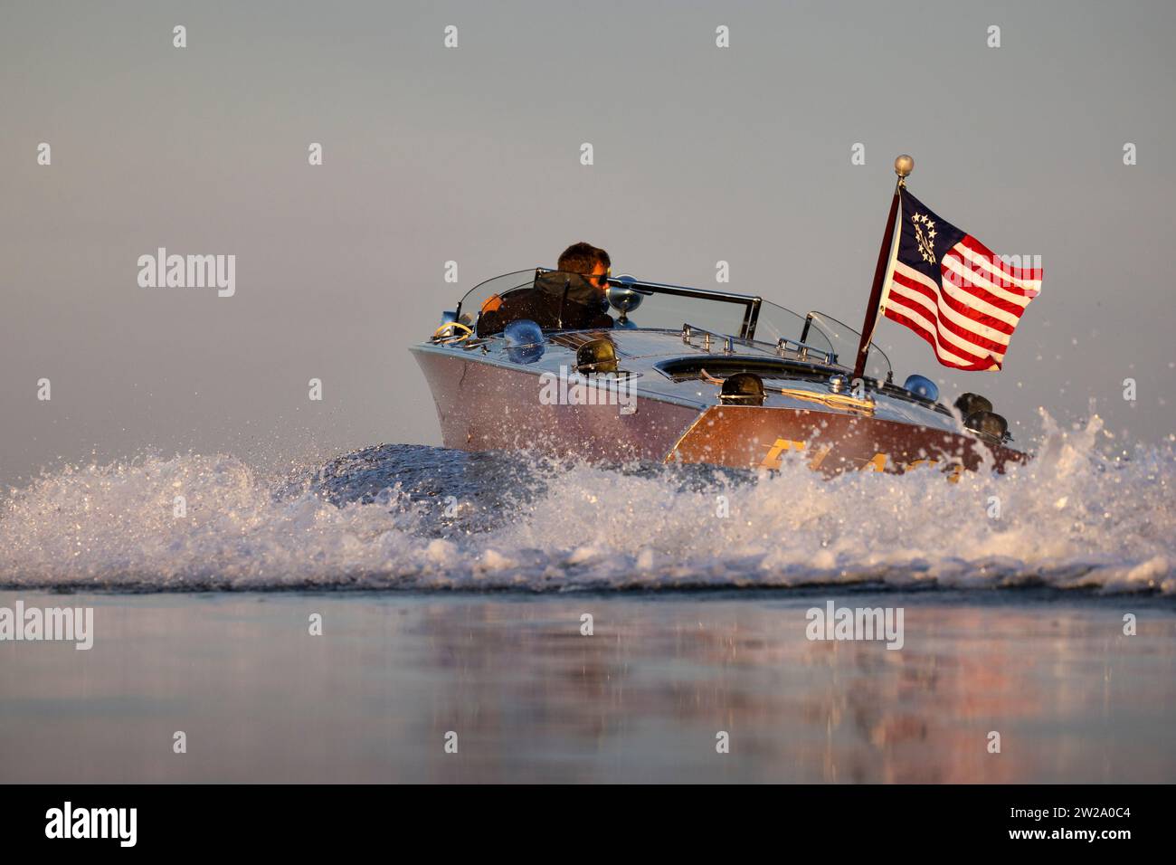 An antique, wooden Hacker-Craft speedboat turning sharply and going ...