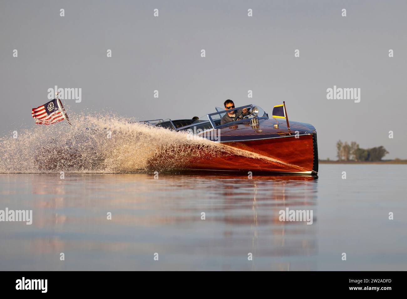 A vintage, wood speedboat turning sharply on a calm lake Stock Photo ...