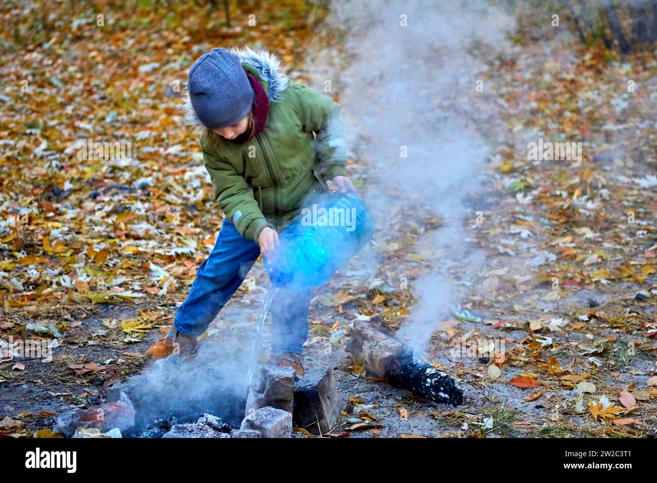 A child puts out a fire after a picnic in the autumn forest Stock Photo ...