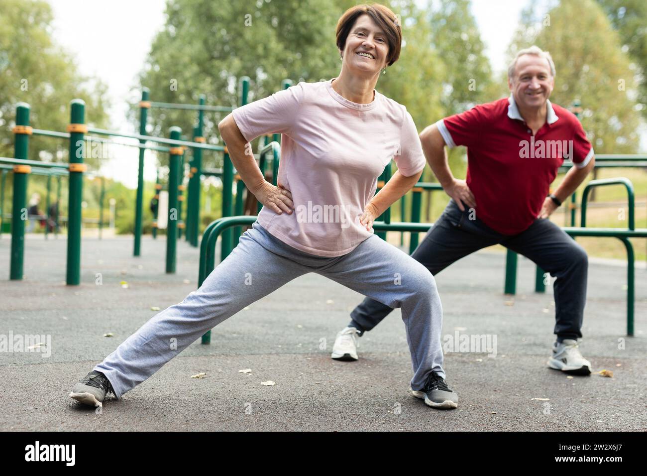 Married couple performs gymnastic exercises together on a sports field ...