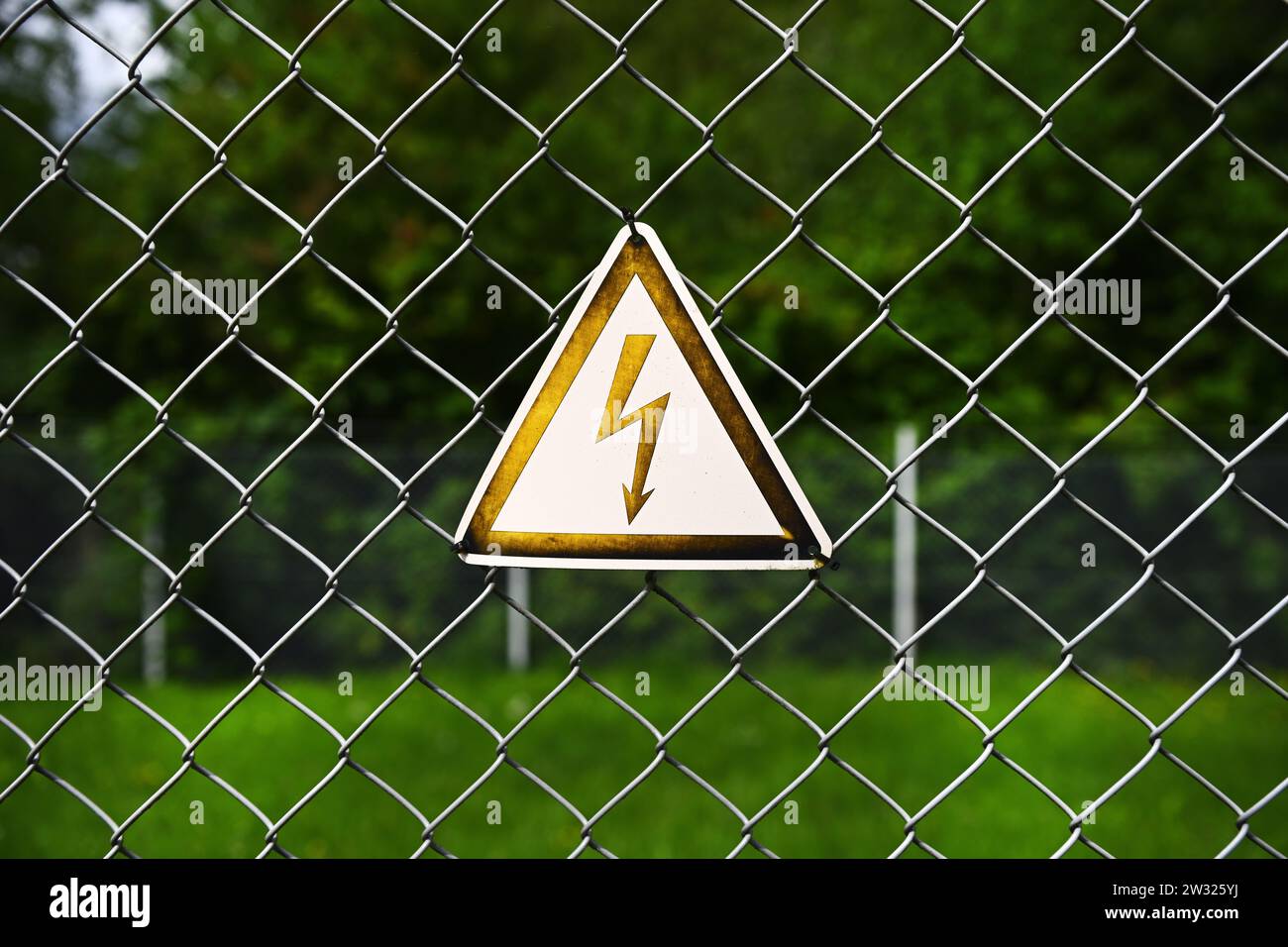 Schild mit Strompfeil an einem Zaun, Symbolfoto Stromversorgung und ...