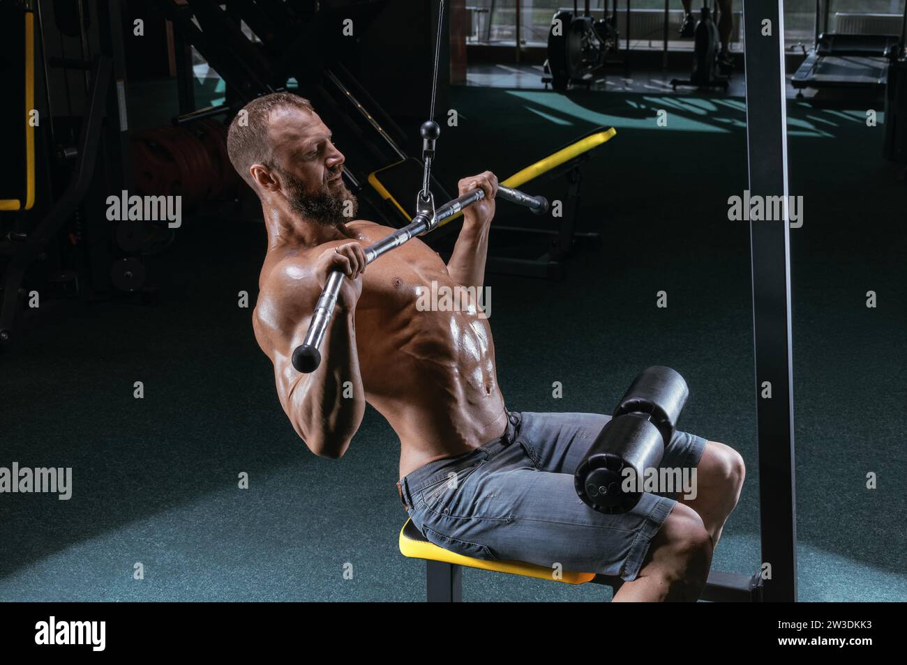 Professional athlete performs an exercise in the gym. Pulls the bar to ...