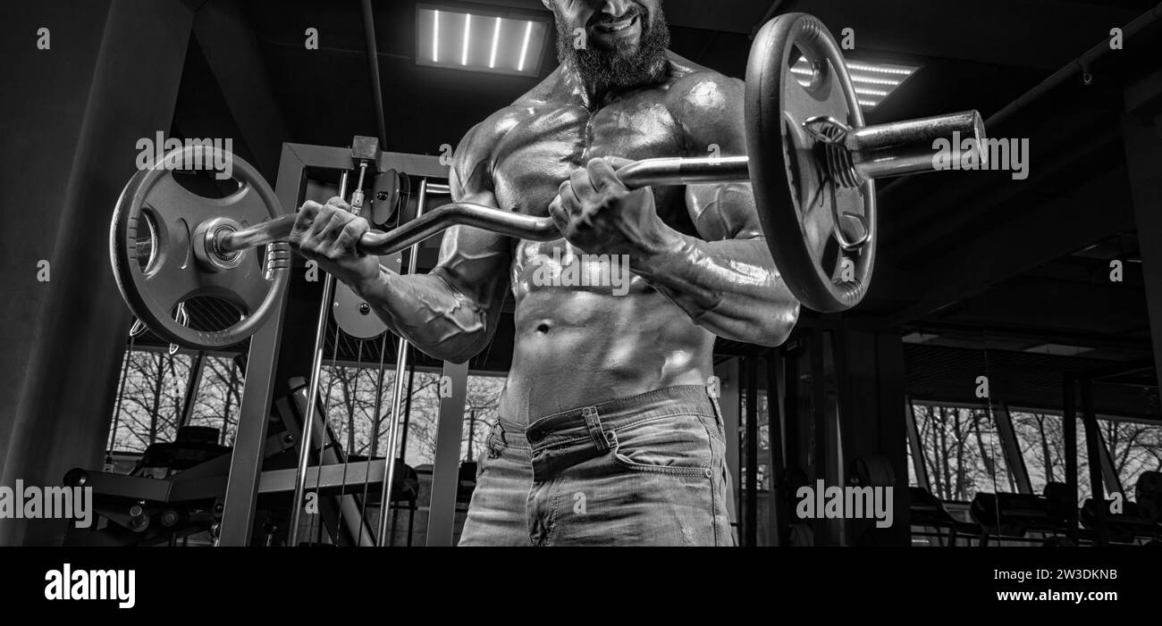 Powerful bodybuilder posing in the gym with a barbell. Bodybuilding ...