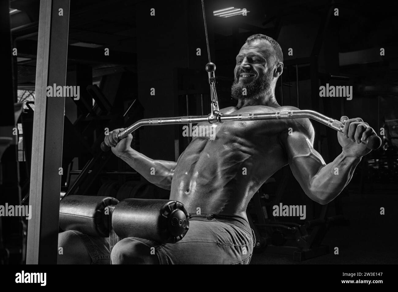 Professional athlete performs an exercise in the gym. Pulls the bar to ...